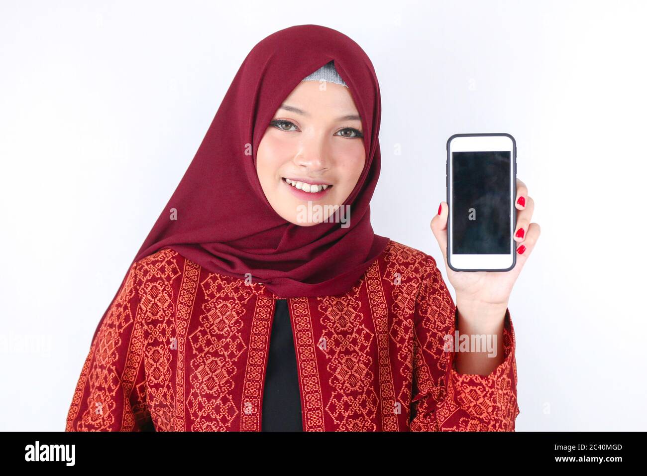 Young Asian Islam woman is smiling showing smartphone standing on white ...