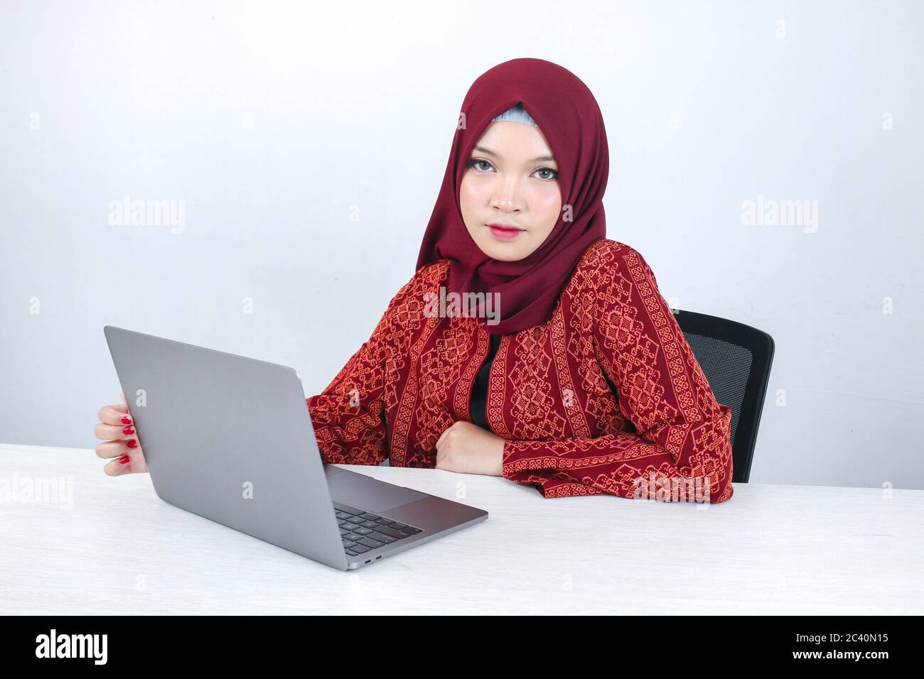 Young Asian Islam woman is sitting working on laptop with serious ...