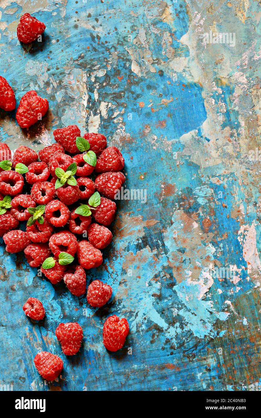 Heart shape made of premium raspberries on a blue background. Close up ...