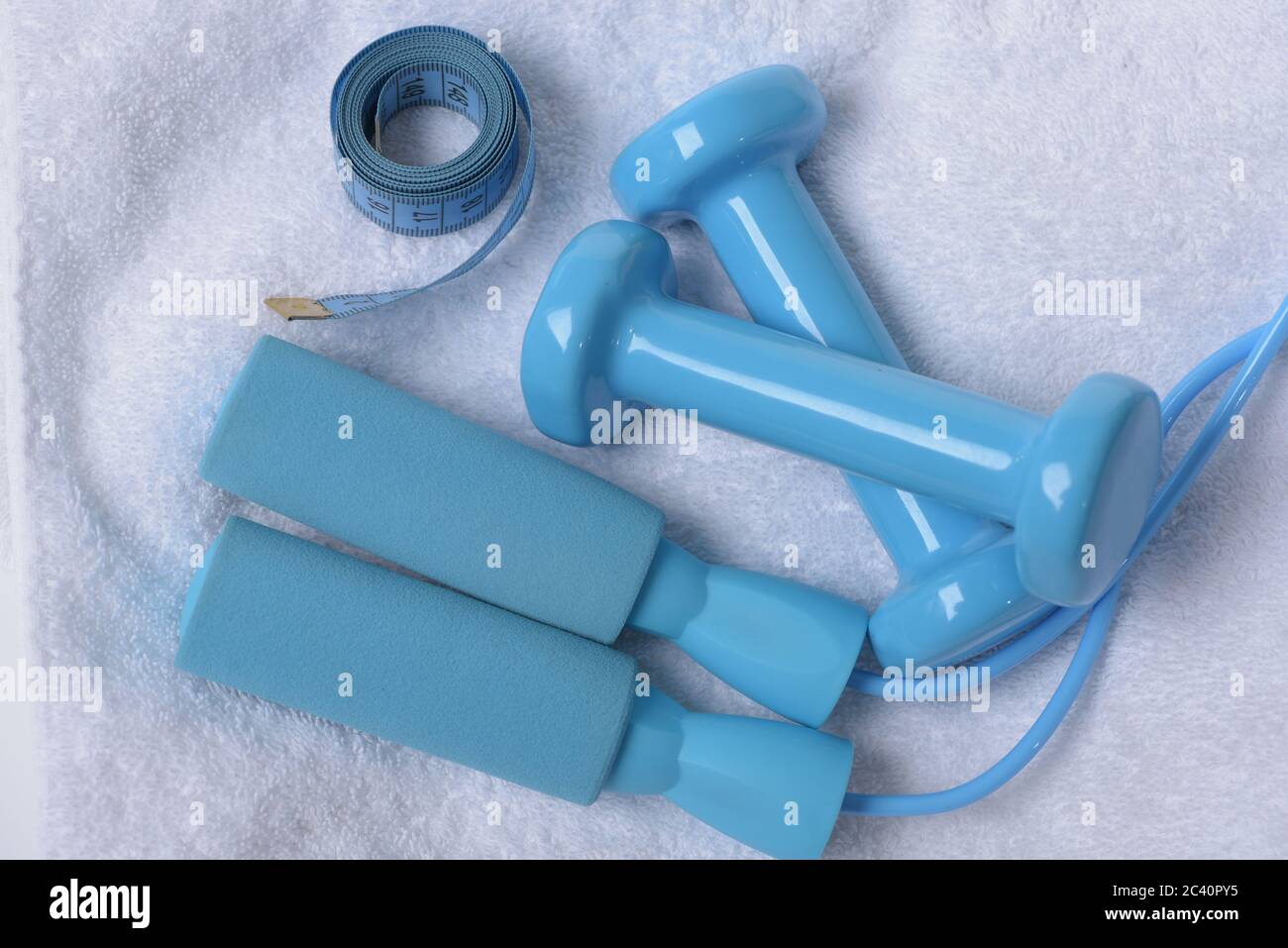 Dumbbells, skipping rope and tape measure in cyan color on light soft ...