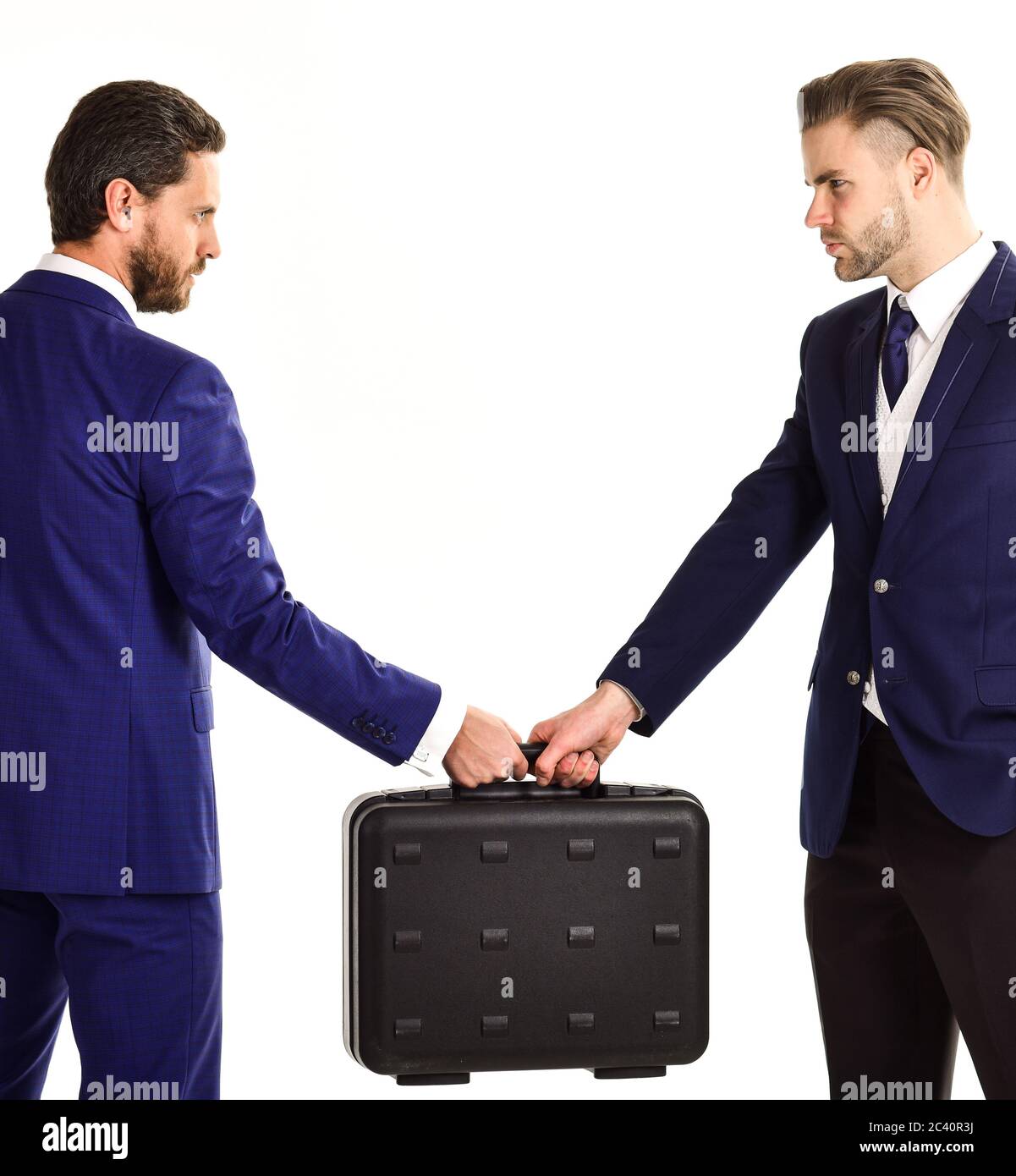Businessmen with serious faces hold black briefcase. Business exchange ...
