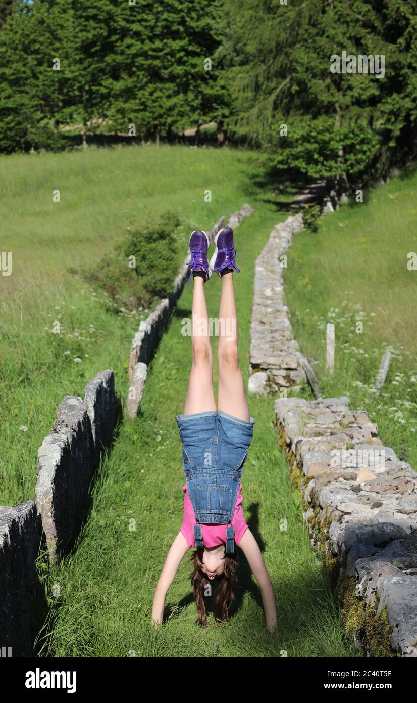 athletic girl does exercises with the head down and the legs up along a ...