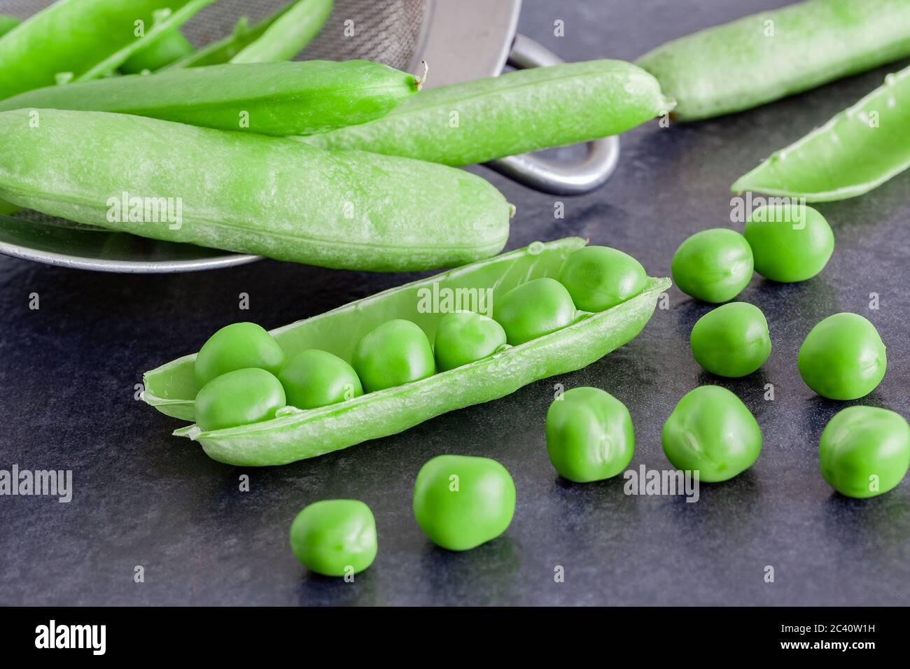 open pea pods on a dark table with a sieve in the background Stock ...