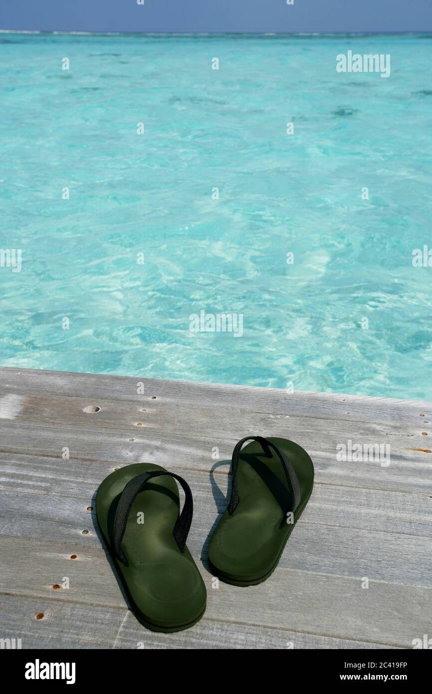 Flip-flops stand on a wooden walkway, Indian Ocean in the background ...