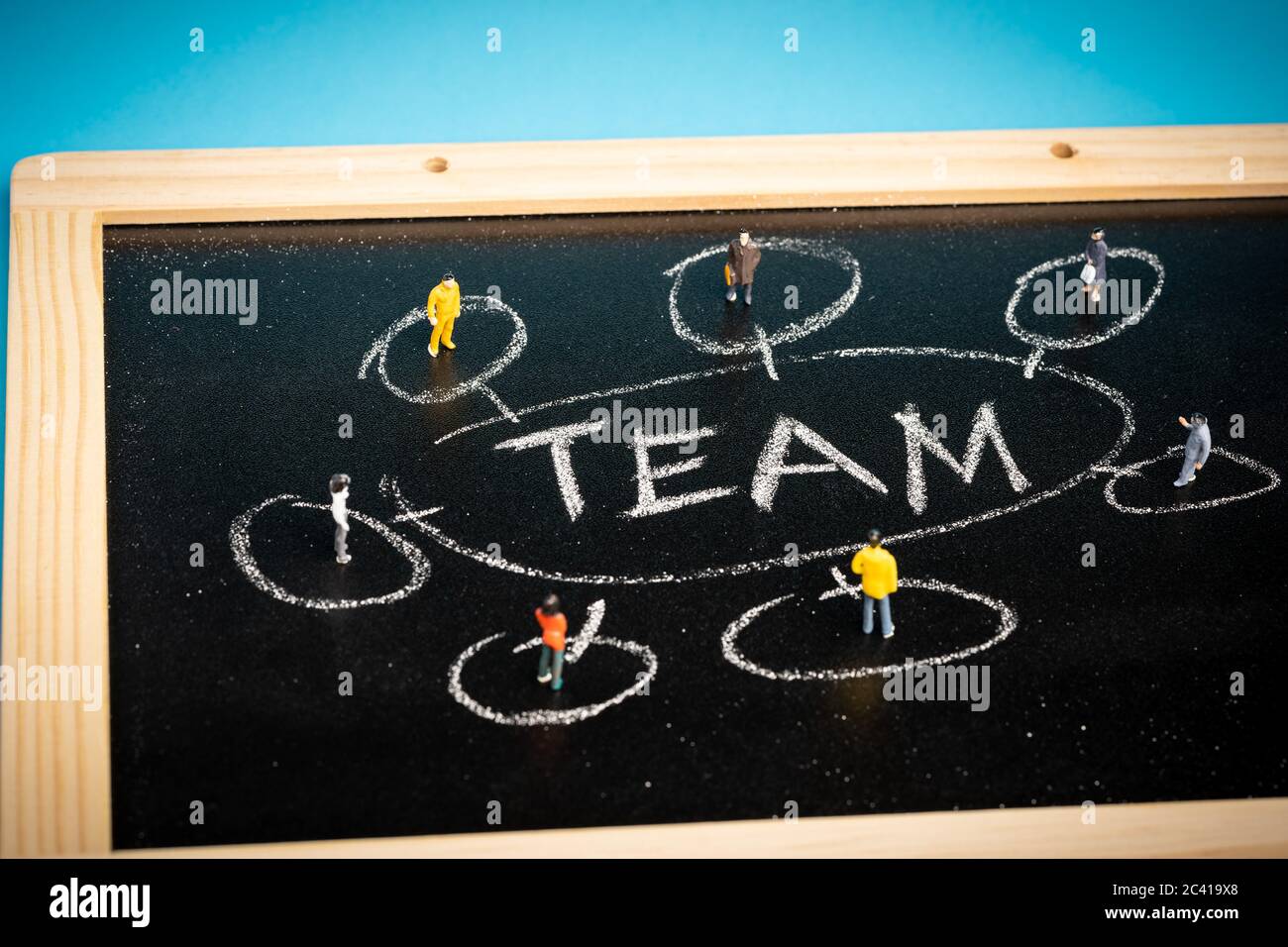 Teamwork concept: a group of miniatures person on a chalkboard with ...