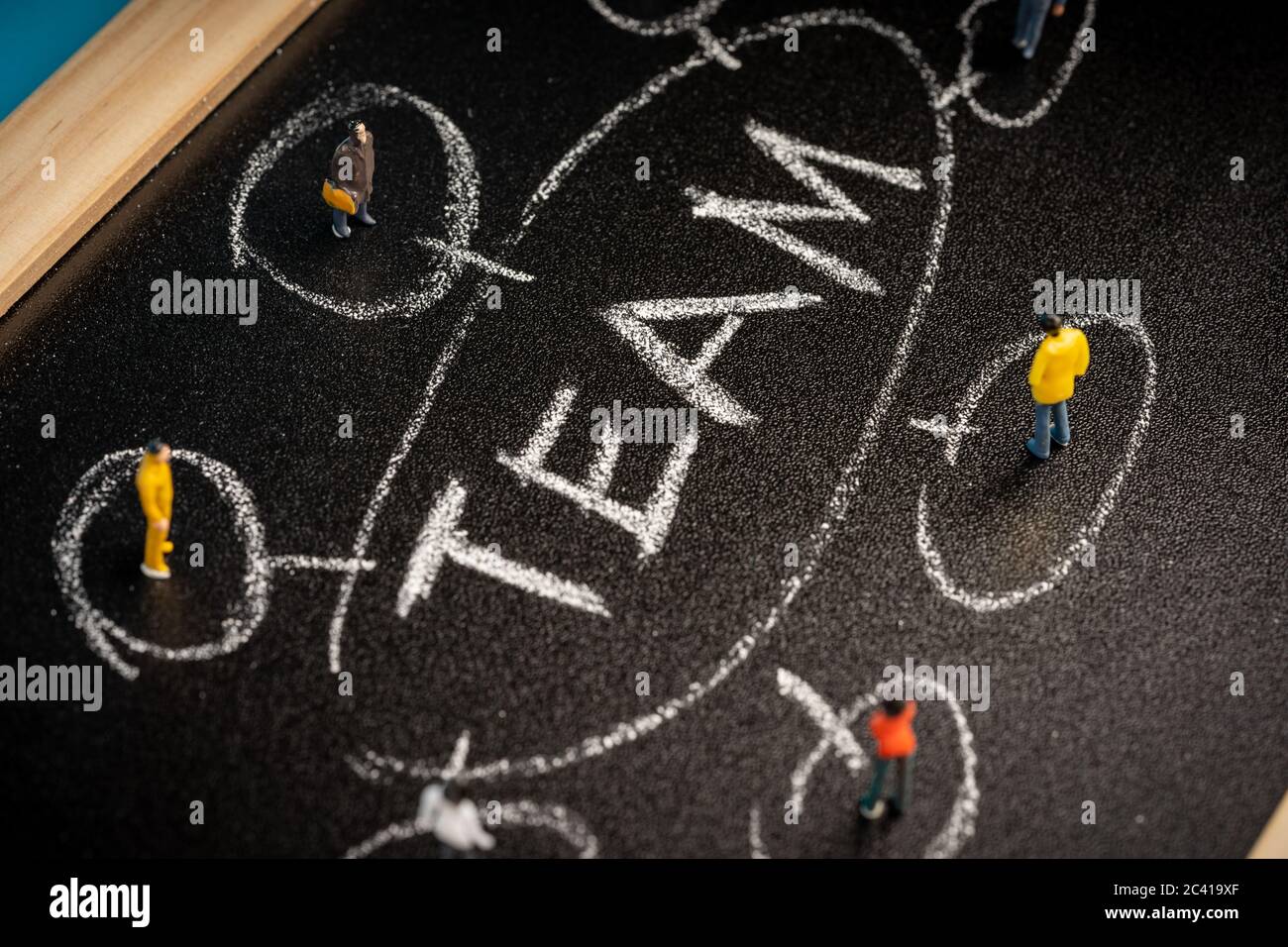 Teamwork concept: a group of miniatures person on a chalkboard with ...