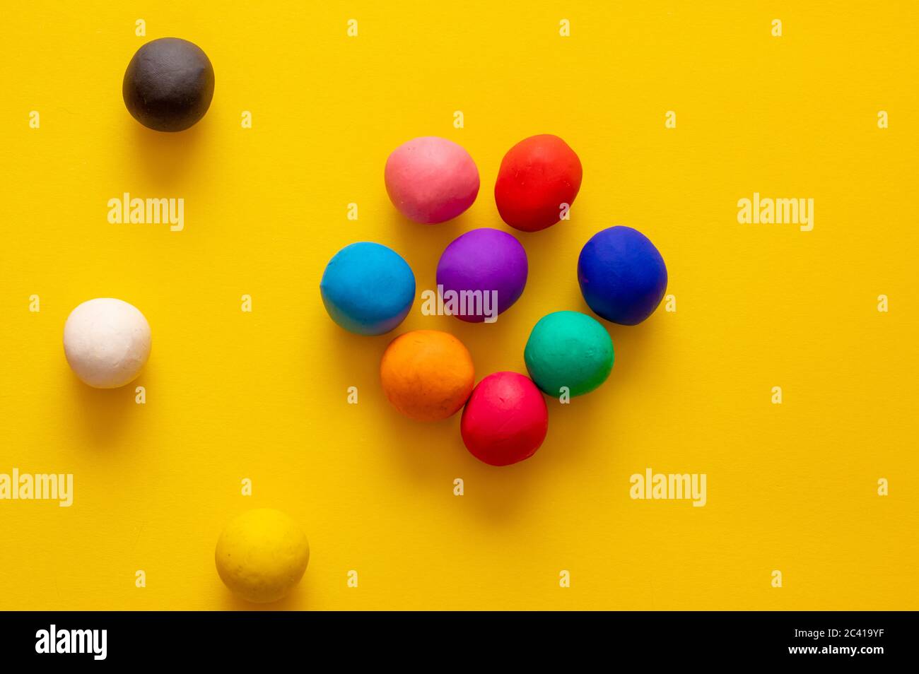 Black, white and yellow balls separated from other colorful balls ...