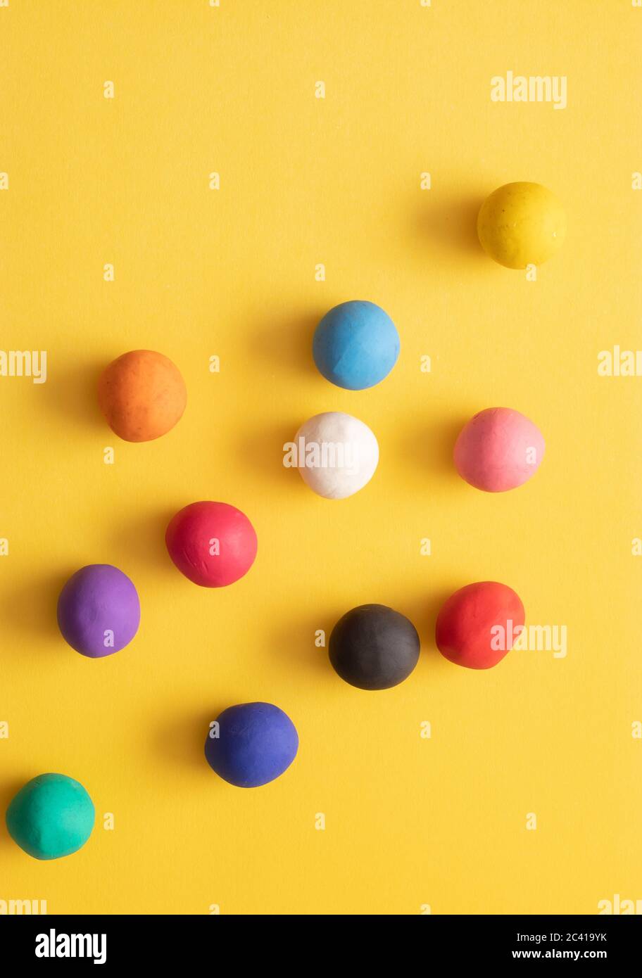 Many different colored plasticine balls on a yellow background ...