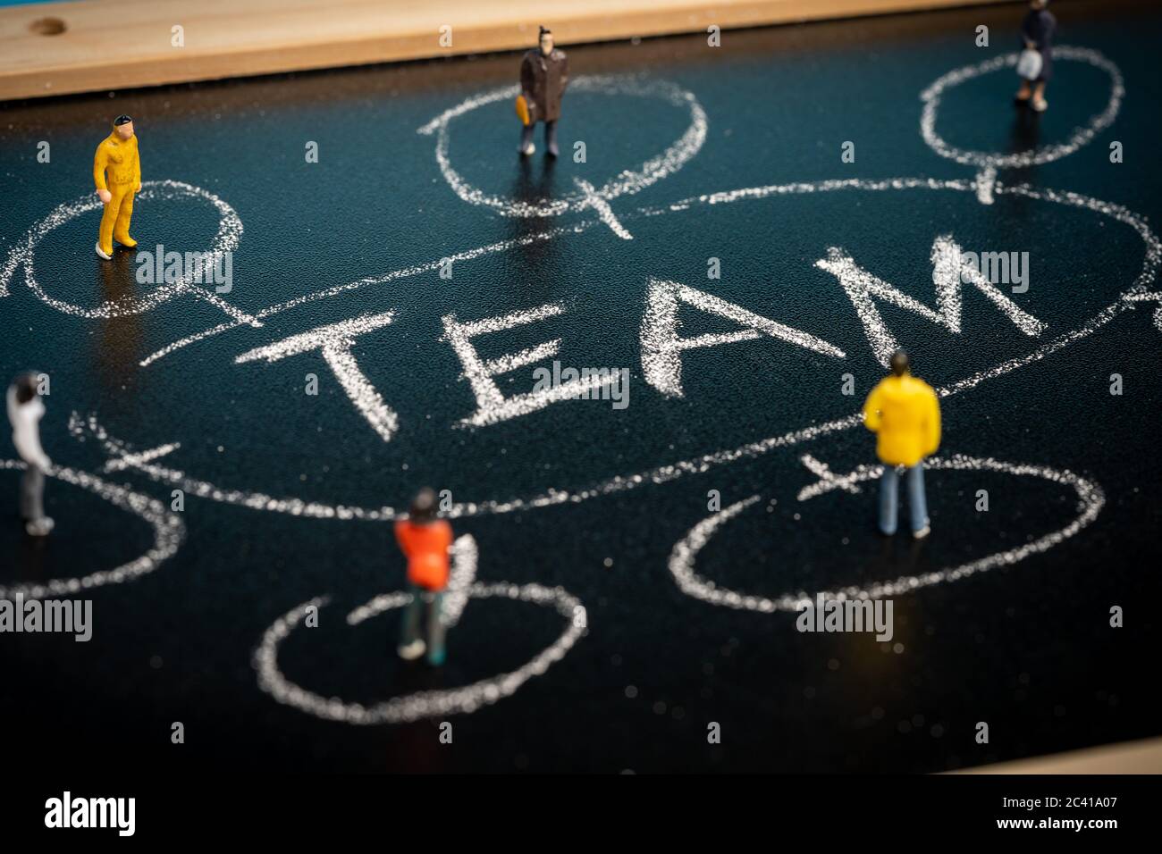 Teamwork concept: a group of miniatures person on a chalkboard with ...