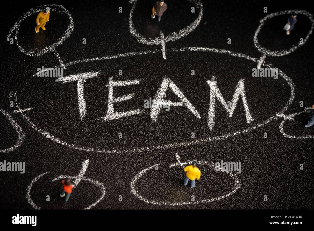 Teamwork concept: a group of miniatures person on a chalkboard with ...