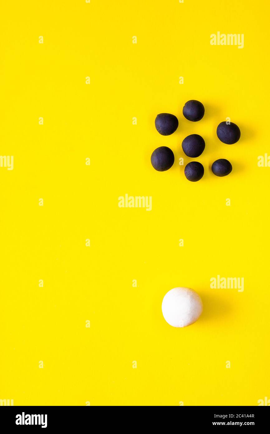 One big white ball and many black smaller plasticine balls in a group ...