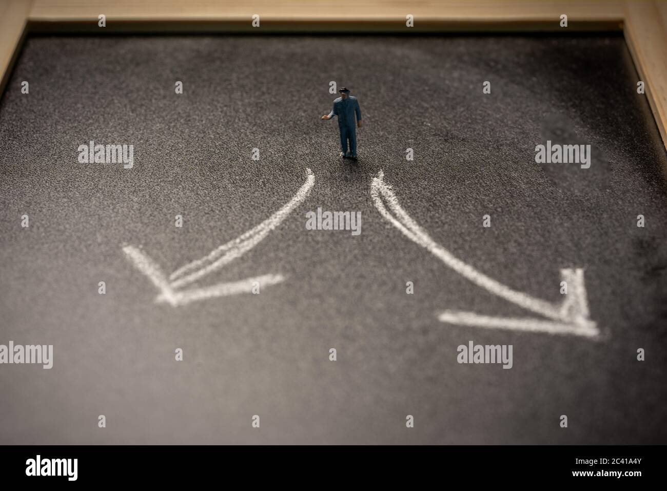 Business concept: Decision making. Miniature man on chalkboard with two ...