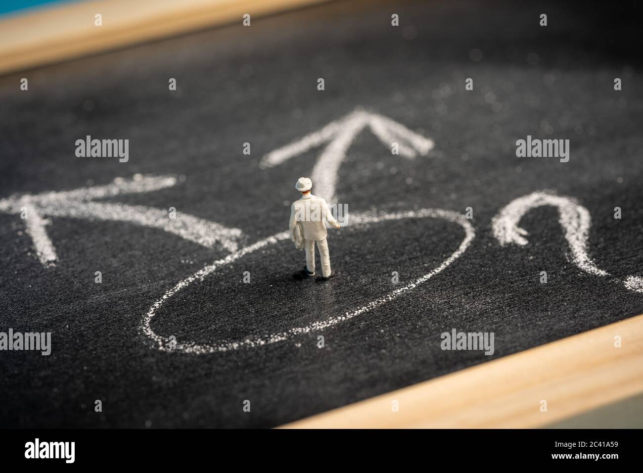 Business concept: Decision making. Miniature man on chalkboard with two ...