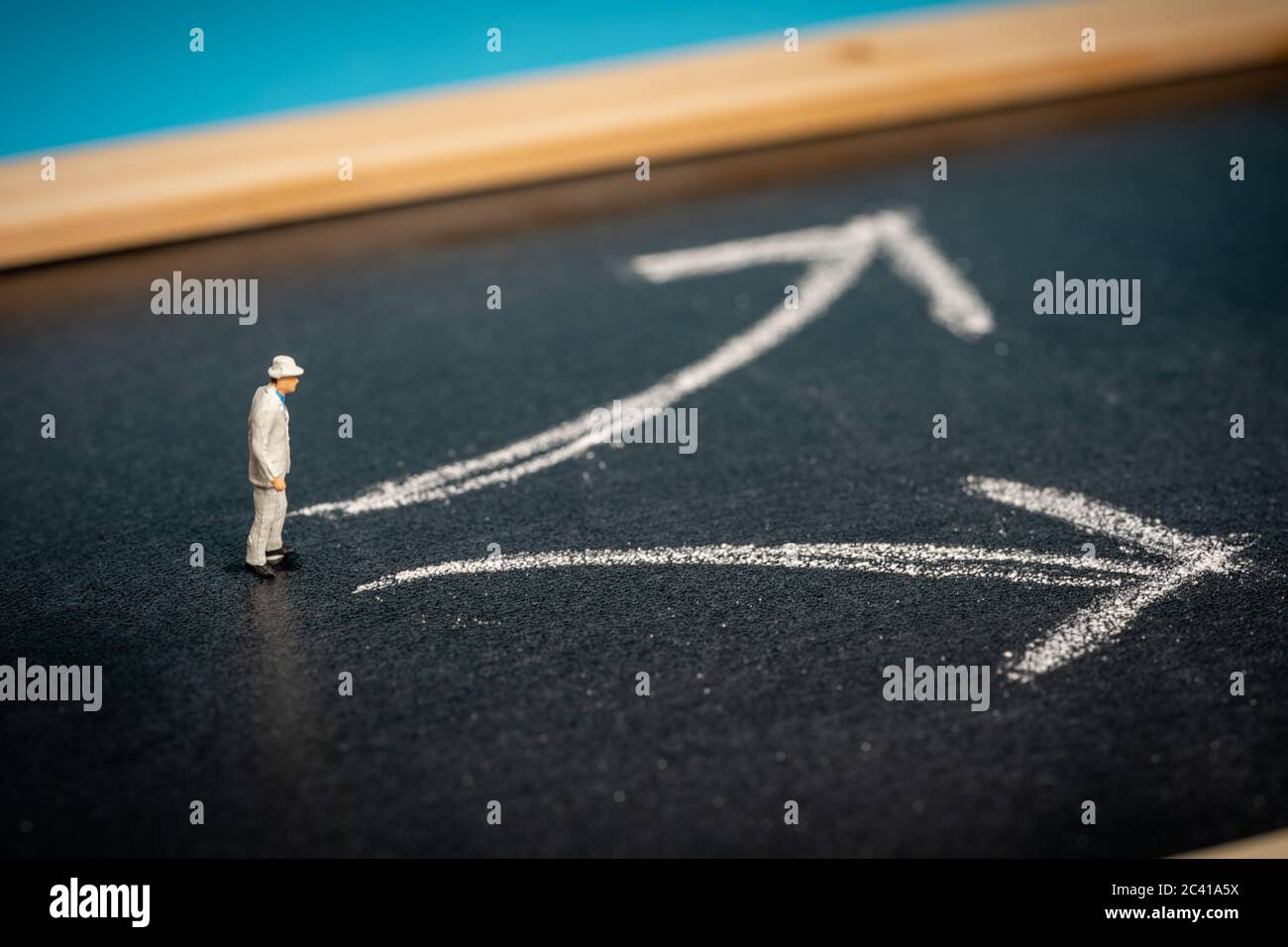 Business concept: Decision making. Miniature man on chalkboard with two ...