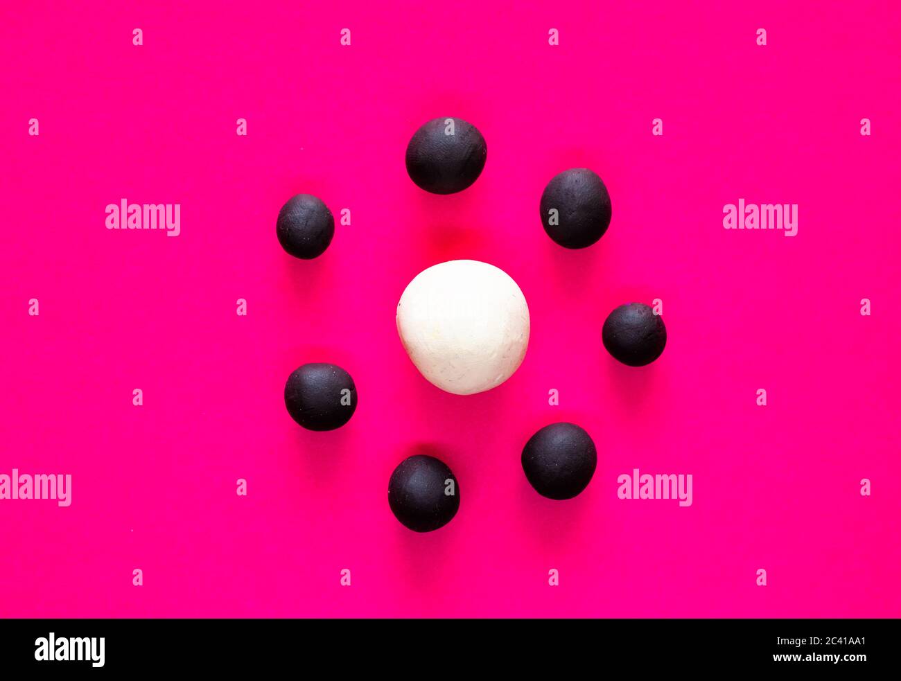 Small Black Balls Surrounding A Large White Plasticine Ball On Pink Vibrant Background Concepts