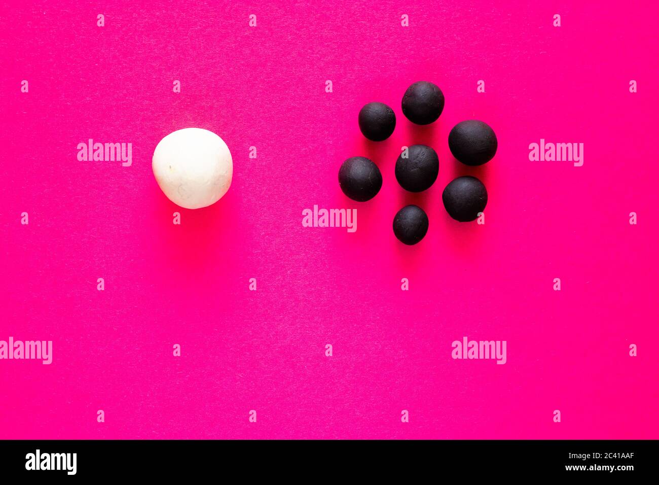Large white ball separated from many smaller black balls. Plasticine ...