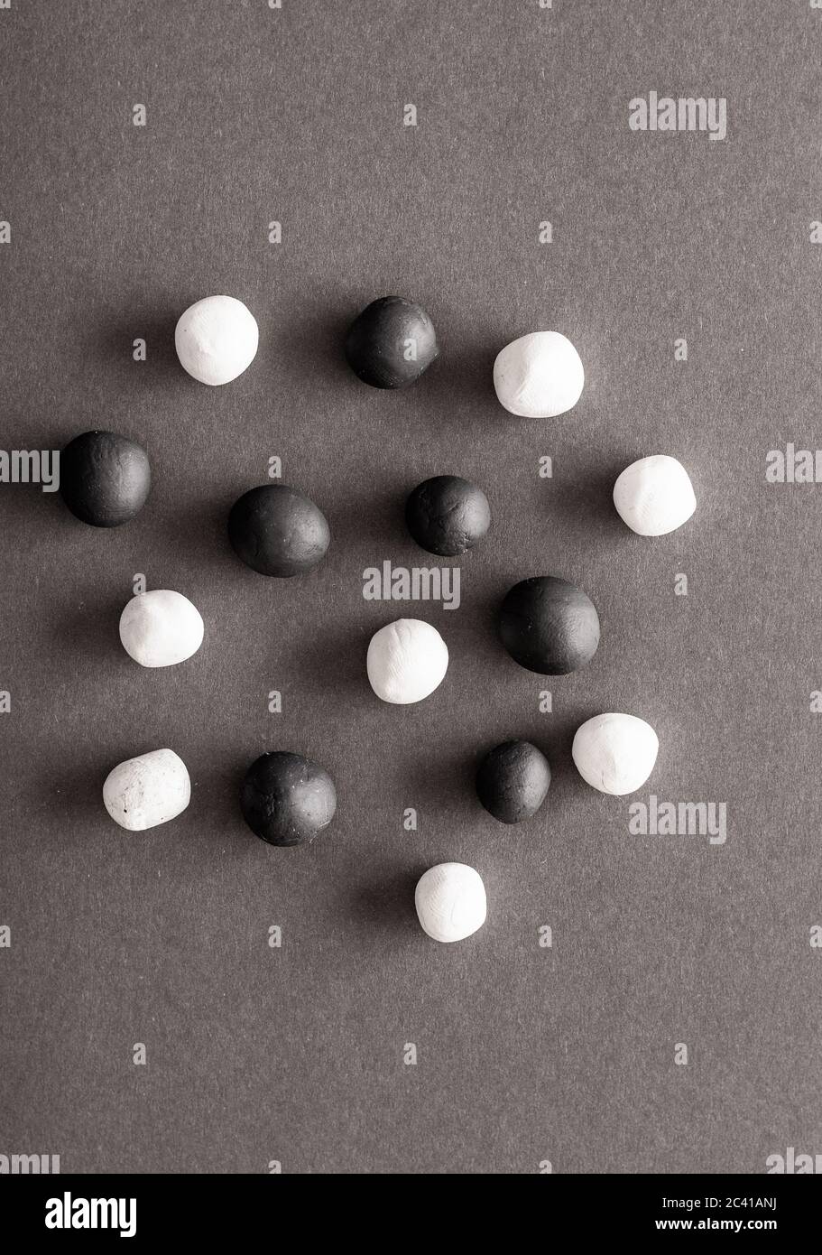 Black and white plasticine balls mixed on a grey background surface ...
