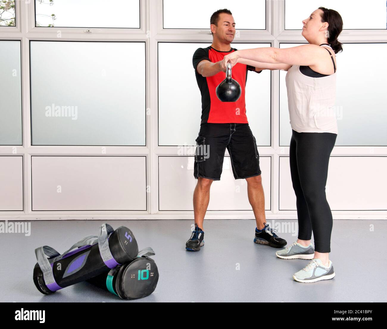 personal trainer helping client at gym in the UK Stock Photo - Alamy