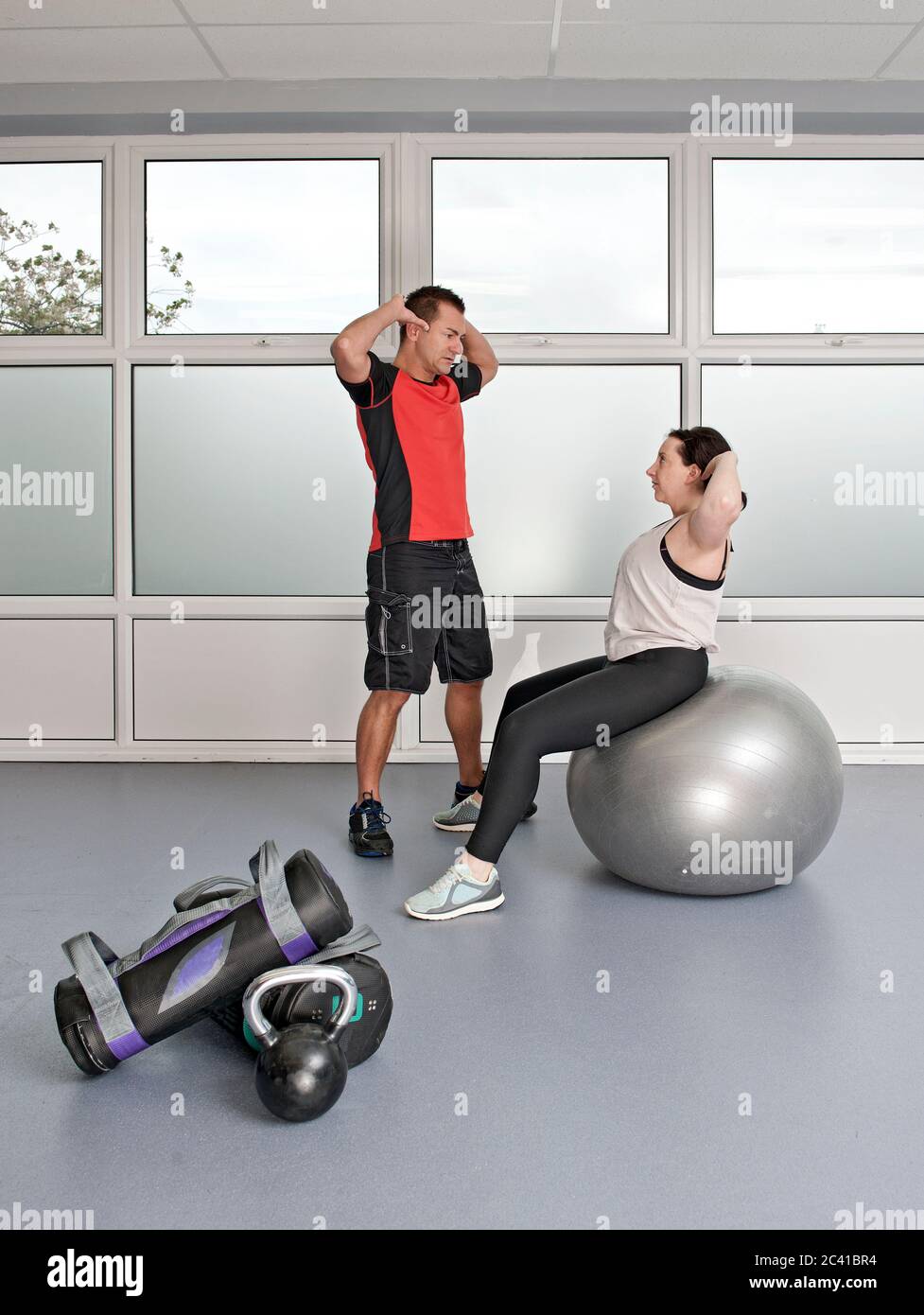 personal trainer helping client at gym in the UK Stock Photo - Alamy