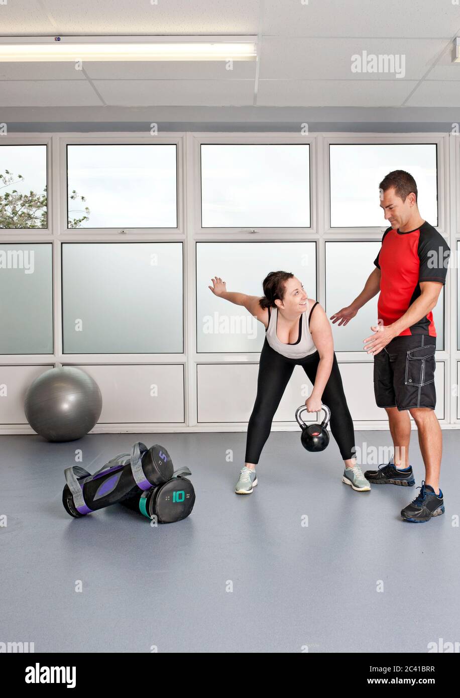 personal trainer helping client at gym in the UK Stock Photo - Alamy