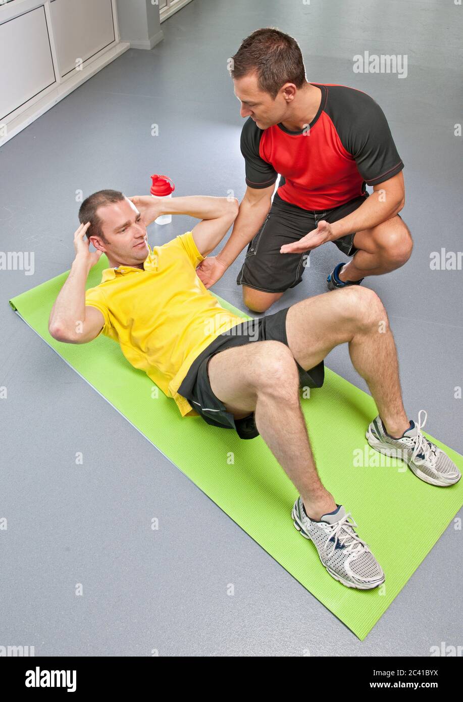 personal trainer helping client in gym Stock Photo - Alamy