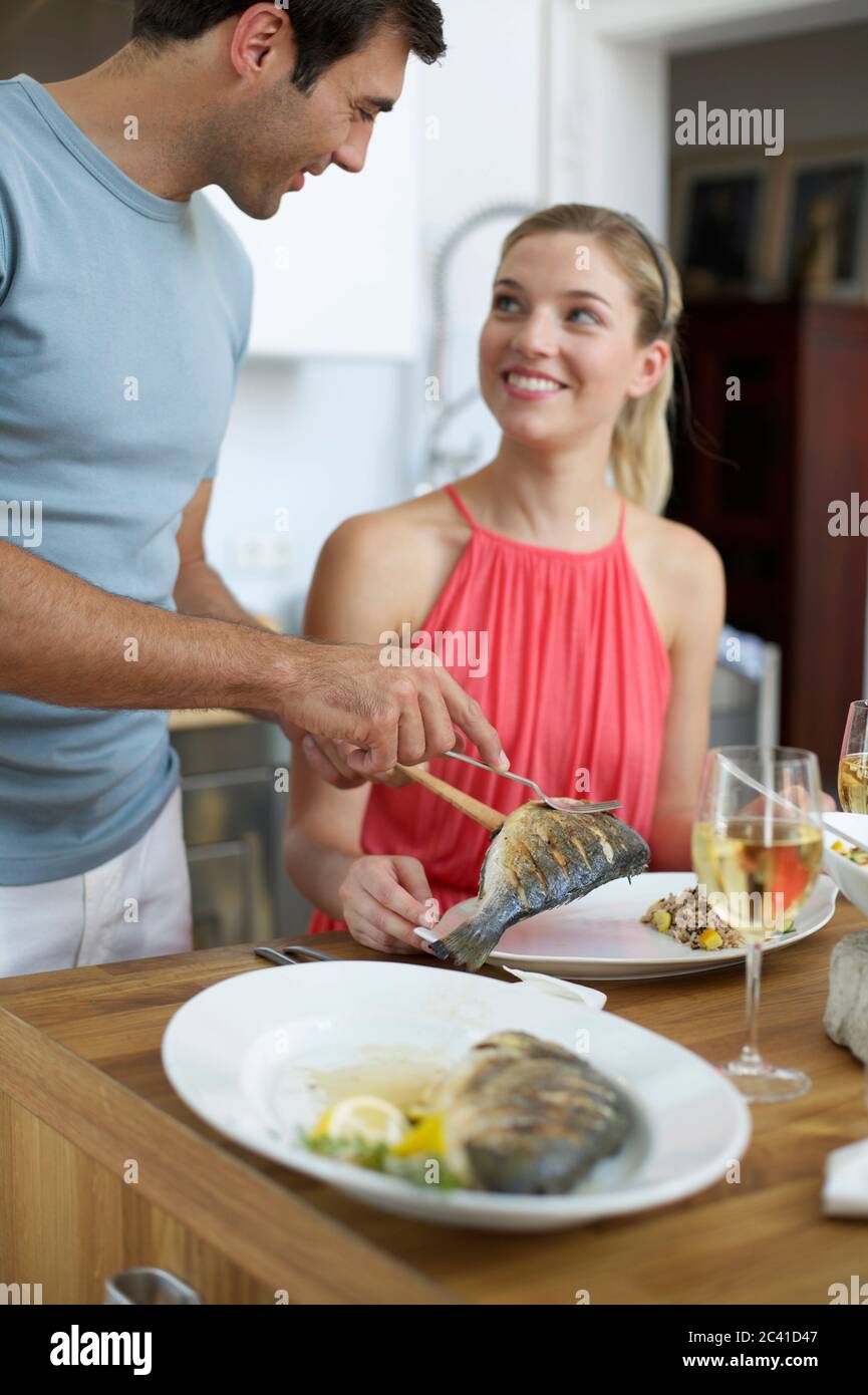 Man serves a fish to woman Stock Photo - Alamy