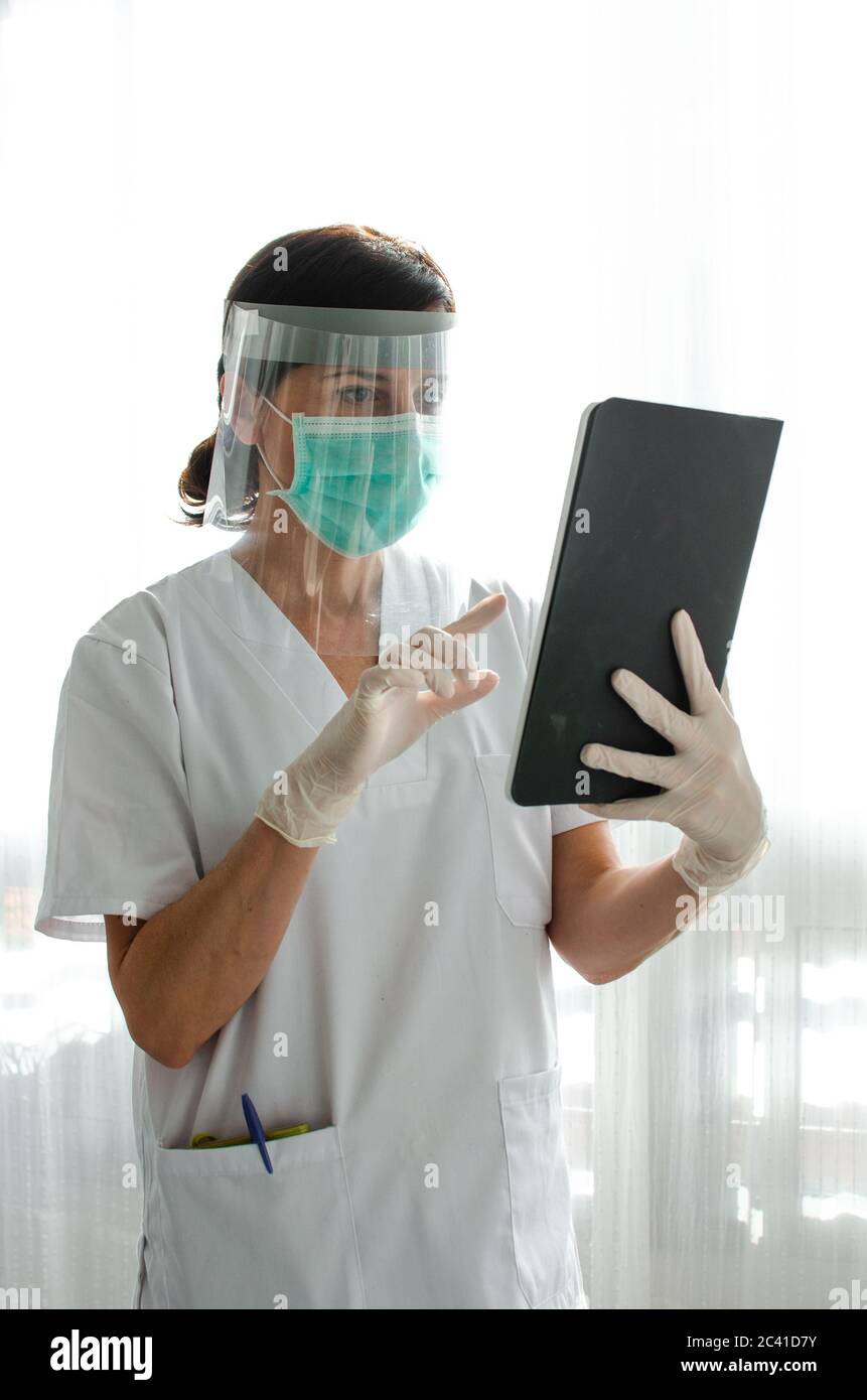 Nurse with a face shield using a tablet Stock Photo - Alamy