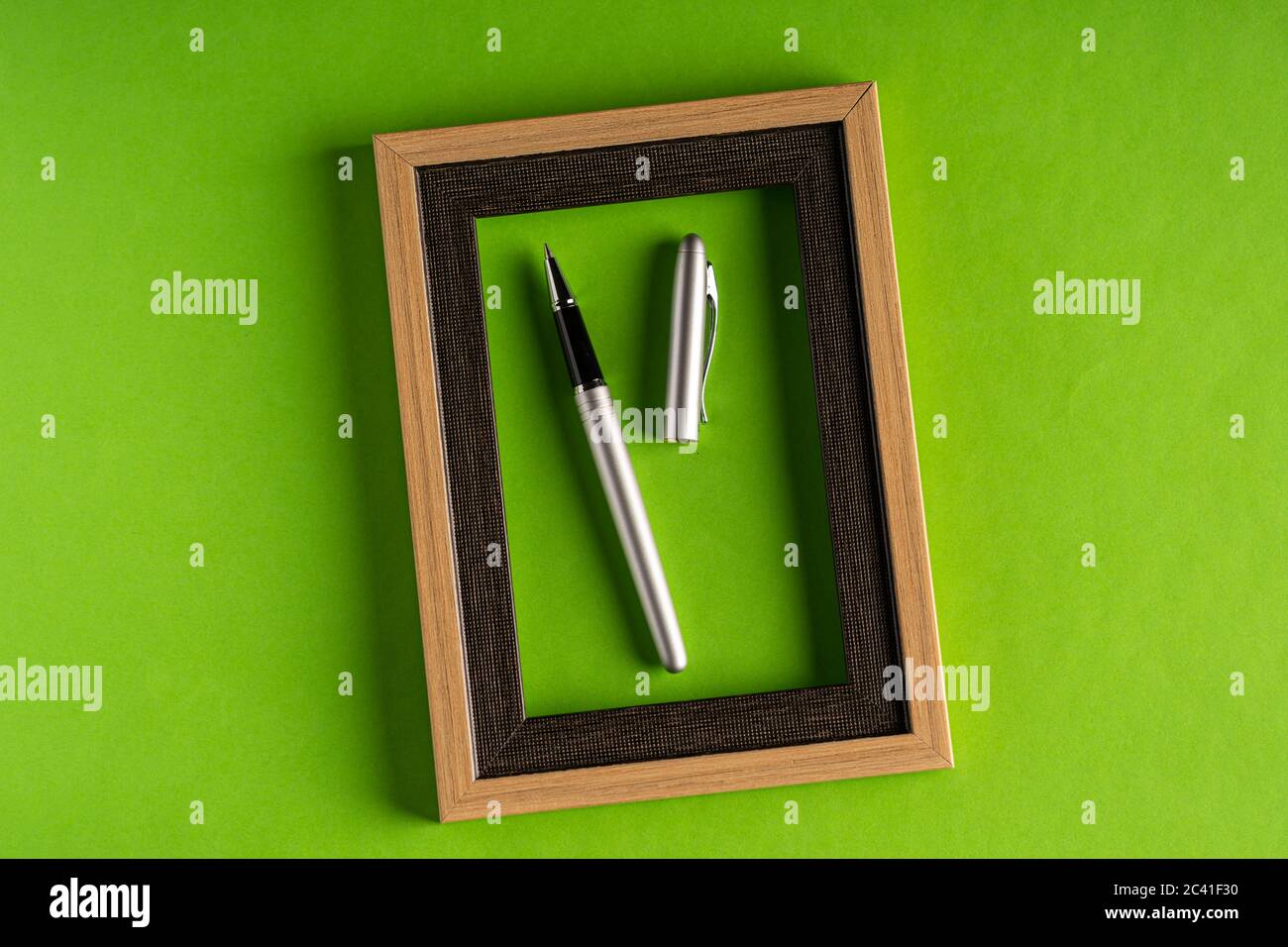 Classy silver pen and empty frame against green background Stock Photo ...