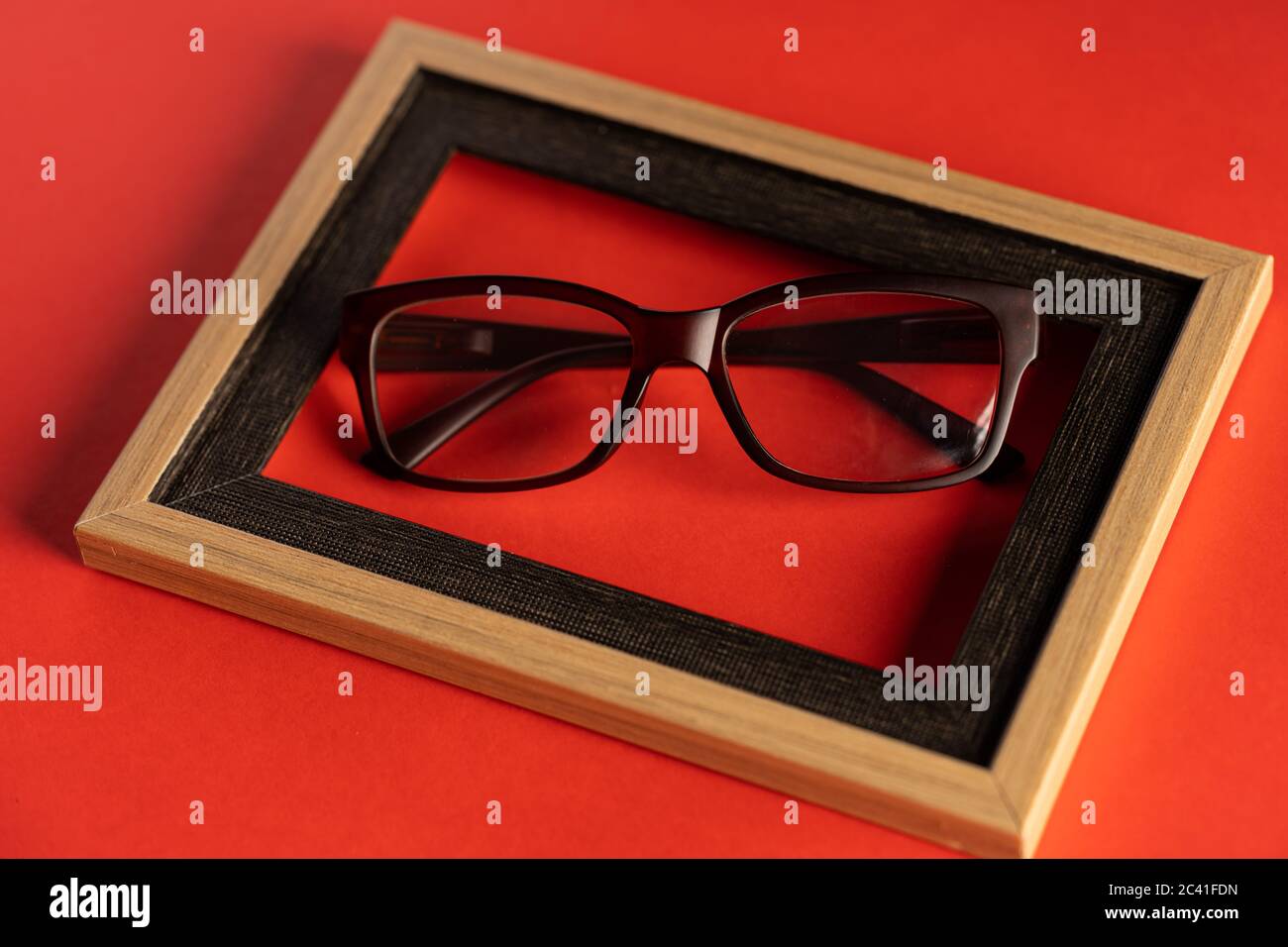 Spectacles and empty photo frame against red background Stock Photo - Alamy