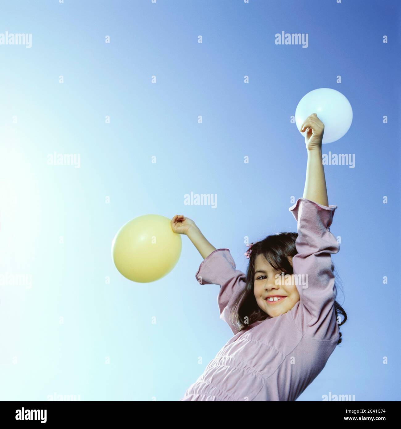 Girl stretches two balloons in the air Stock Photo - Alamy
