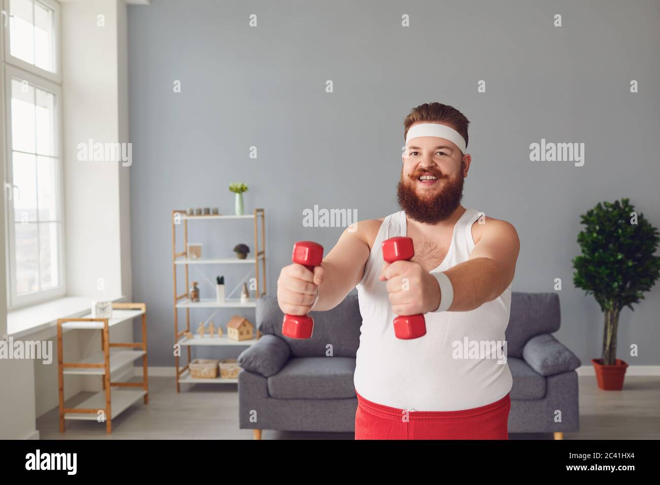 Funny fat man with dumbbells doing exercises in the room Stock Photo ...