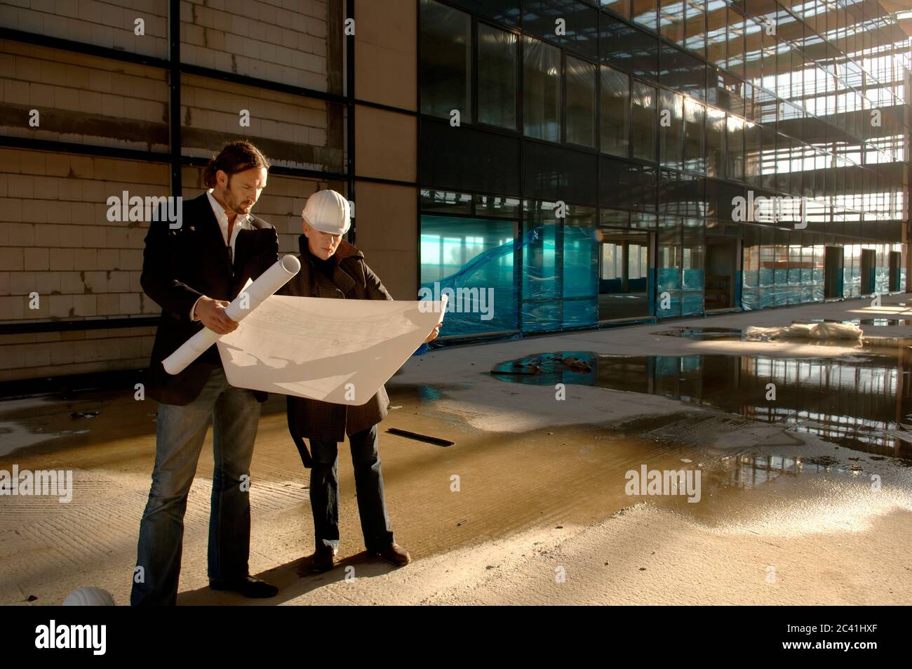 Two architects study blueprints on a construction site Stock Photo - Alamy