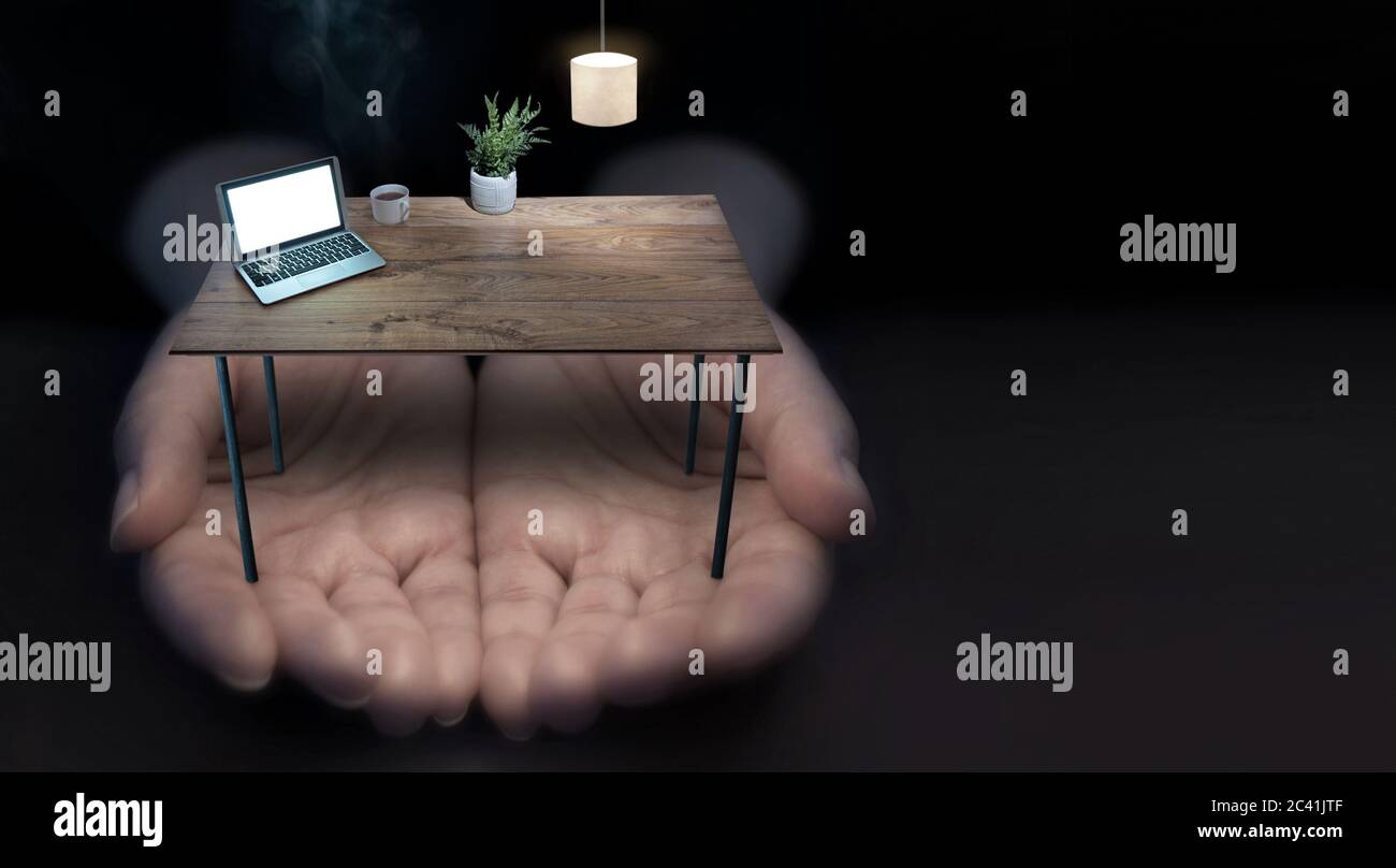 Hands outstretched holding a miniature office desk with laptop and lamp ...