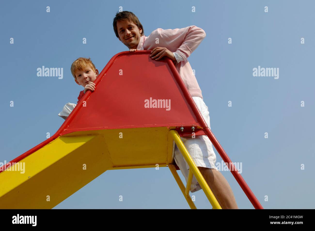 Boy with man on a colorful slide look at the camera Stock Photo - Alamy