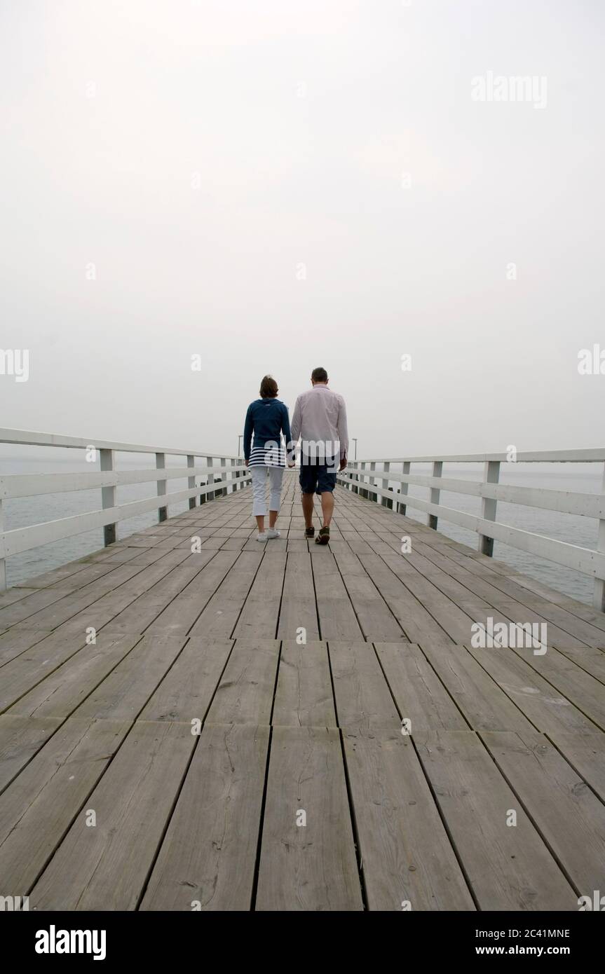 Man and woman stand on a jetty and hold hands - romance - love ...