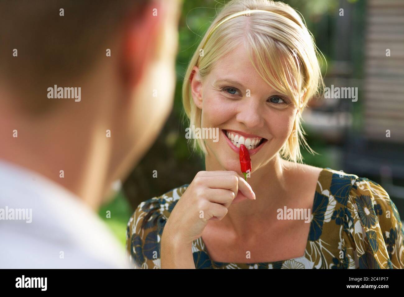 Young woman bites into a chilli pepper Stock Photo - Alamy