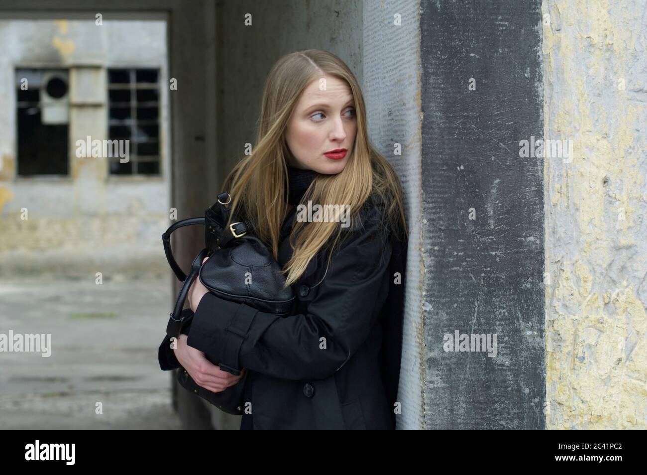 Scared woman looks around a corner Stock Photo - Alamy