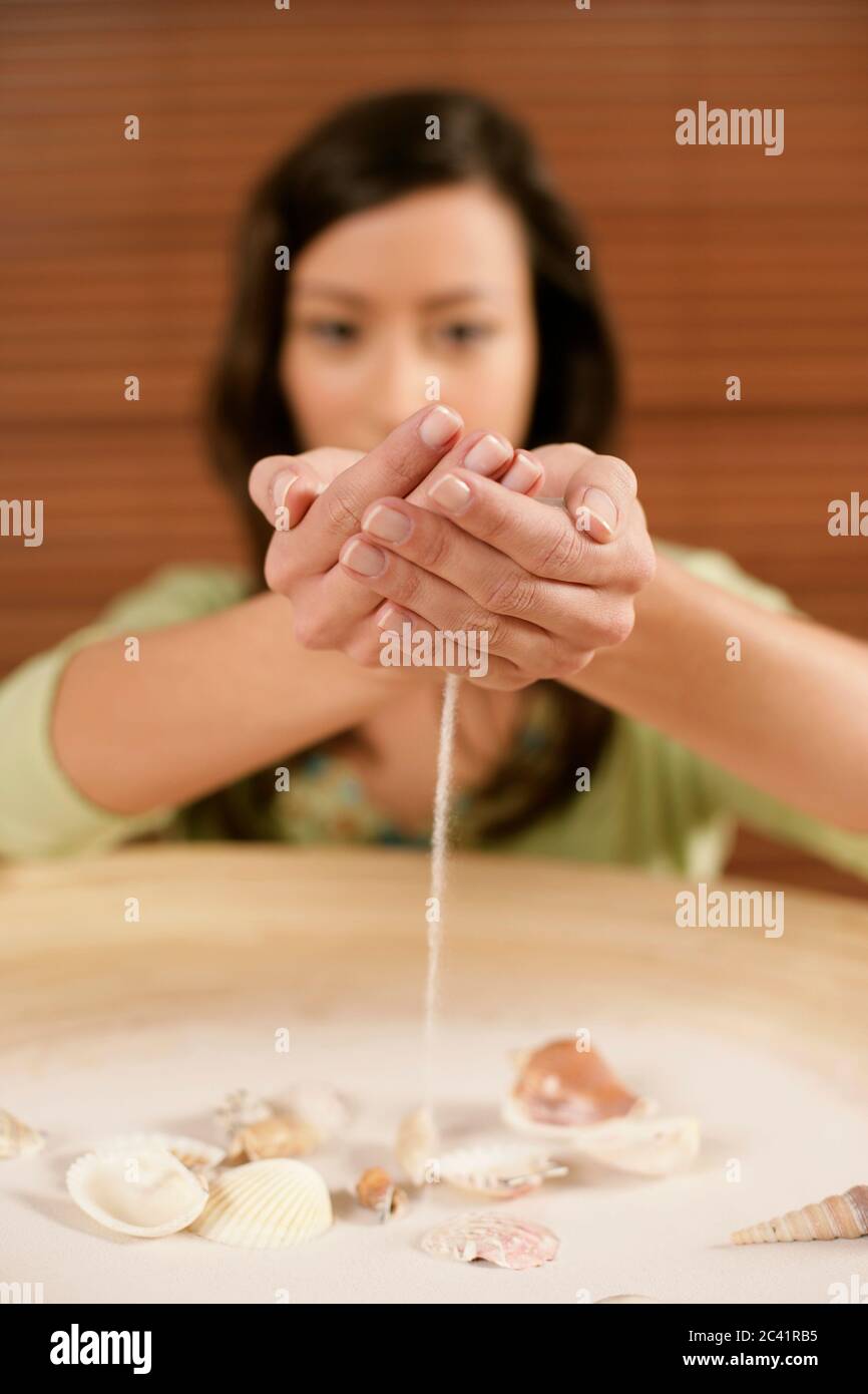 Young woman lets sand trickle through her hands Stock Photo - Alamy