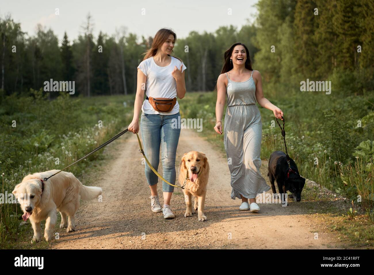 Two happy women on walk with three dogs in park Stock Photo - Alamy