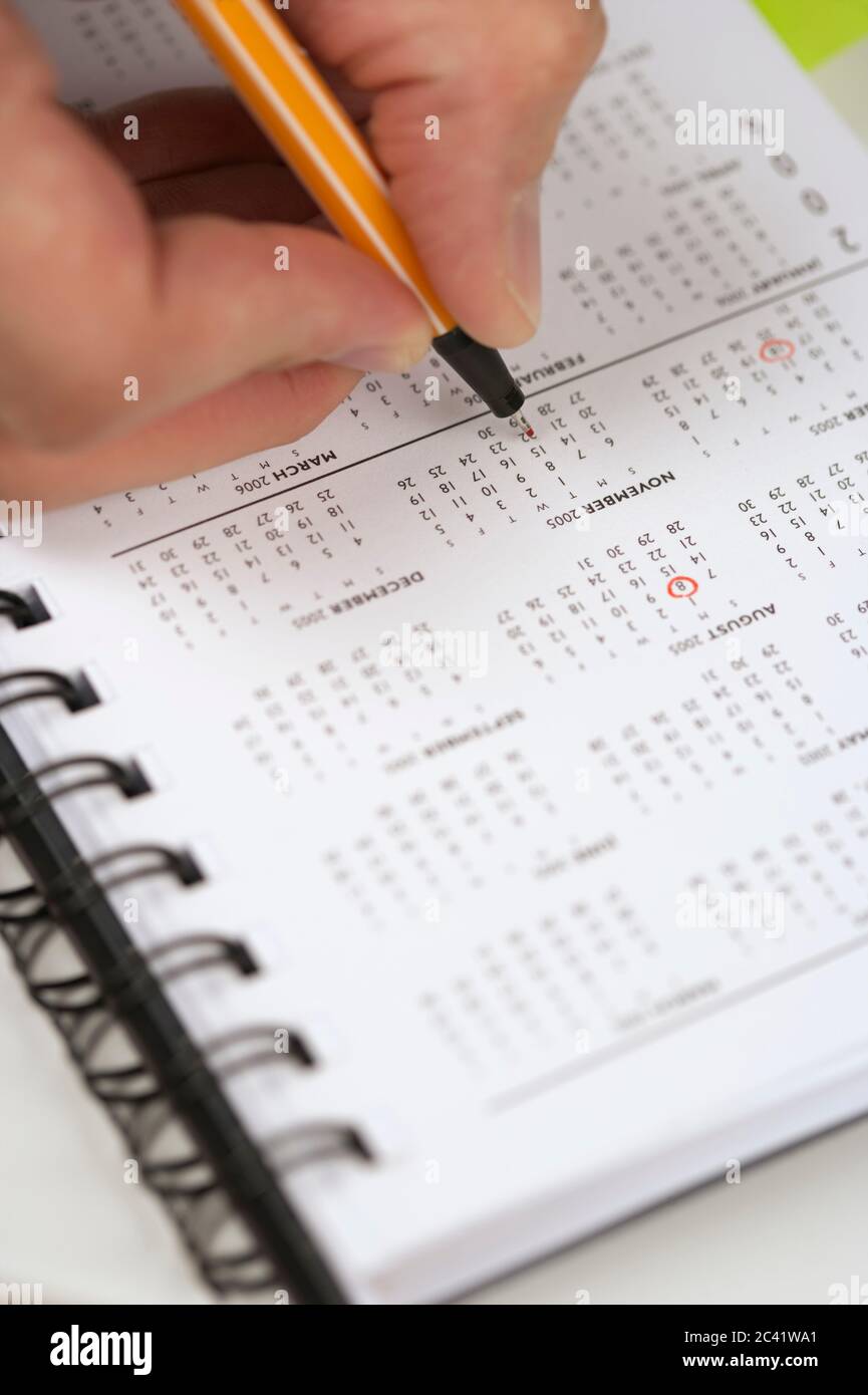 Hand of a man marks dates on the calendar - scheduling Stock Photo - Alamy