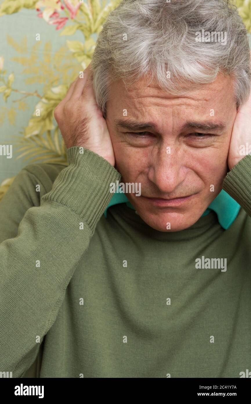 Elderly man covers his ears Stock Photo - Alamy