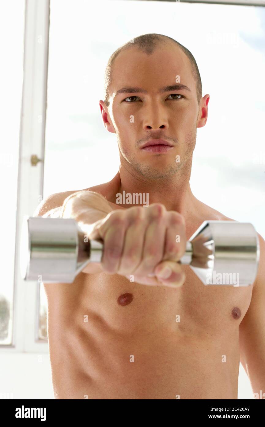 Young man is training with a small dumbbell - building muscle Stock ...