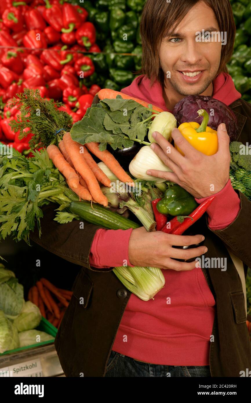 Man stands in front of a vegetable shelf in a supermarket and has an ...