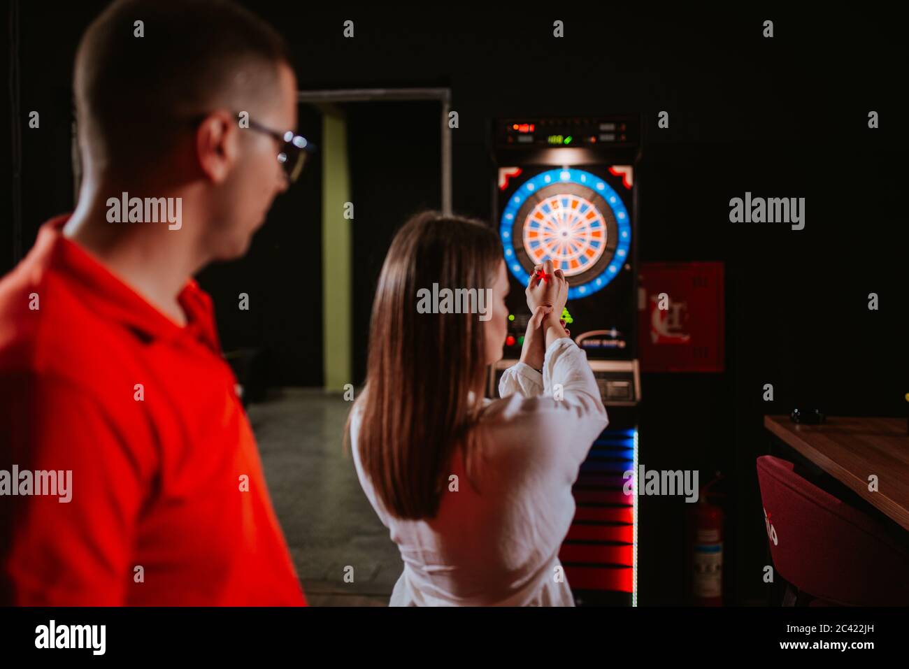 A young beautiful caucasian woman and a man are playing darts. Love and ...