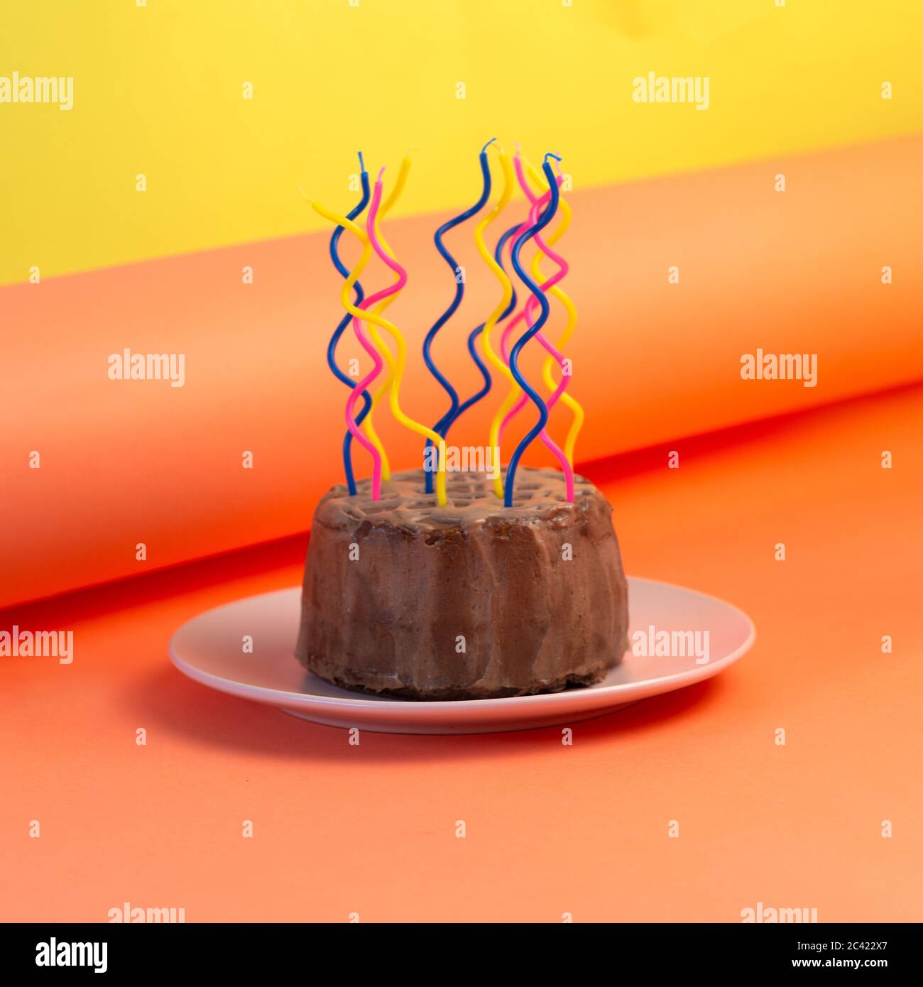 Homemade chocolate birthday cake with curves colorful candles on orange ...