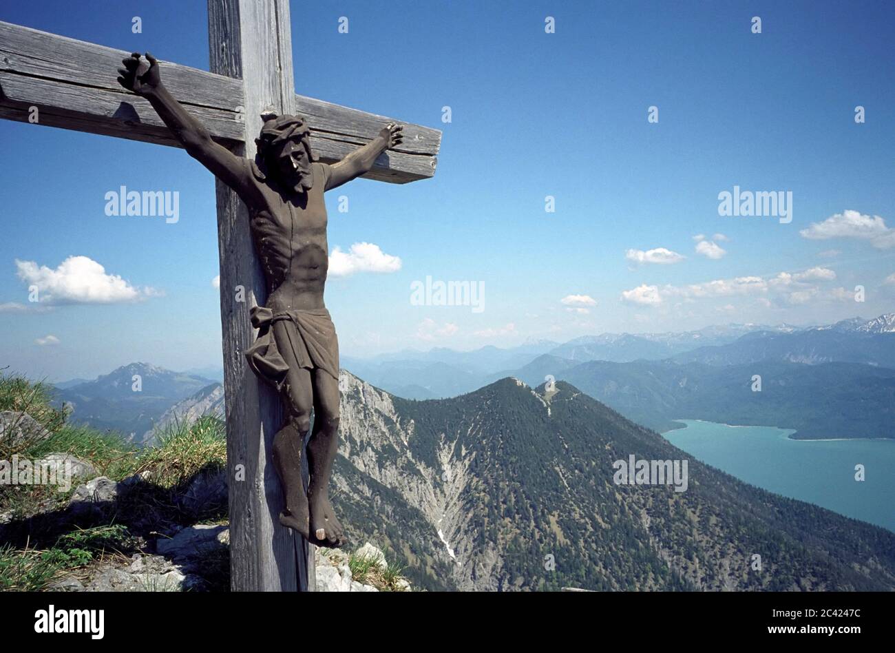 A crucifix on a mountain peak in the background mountain range and lake ...