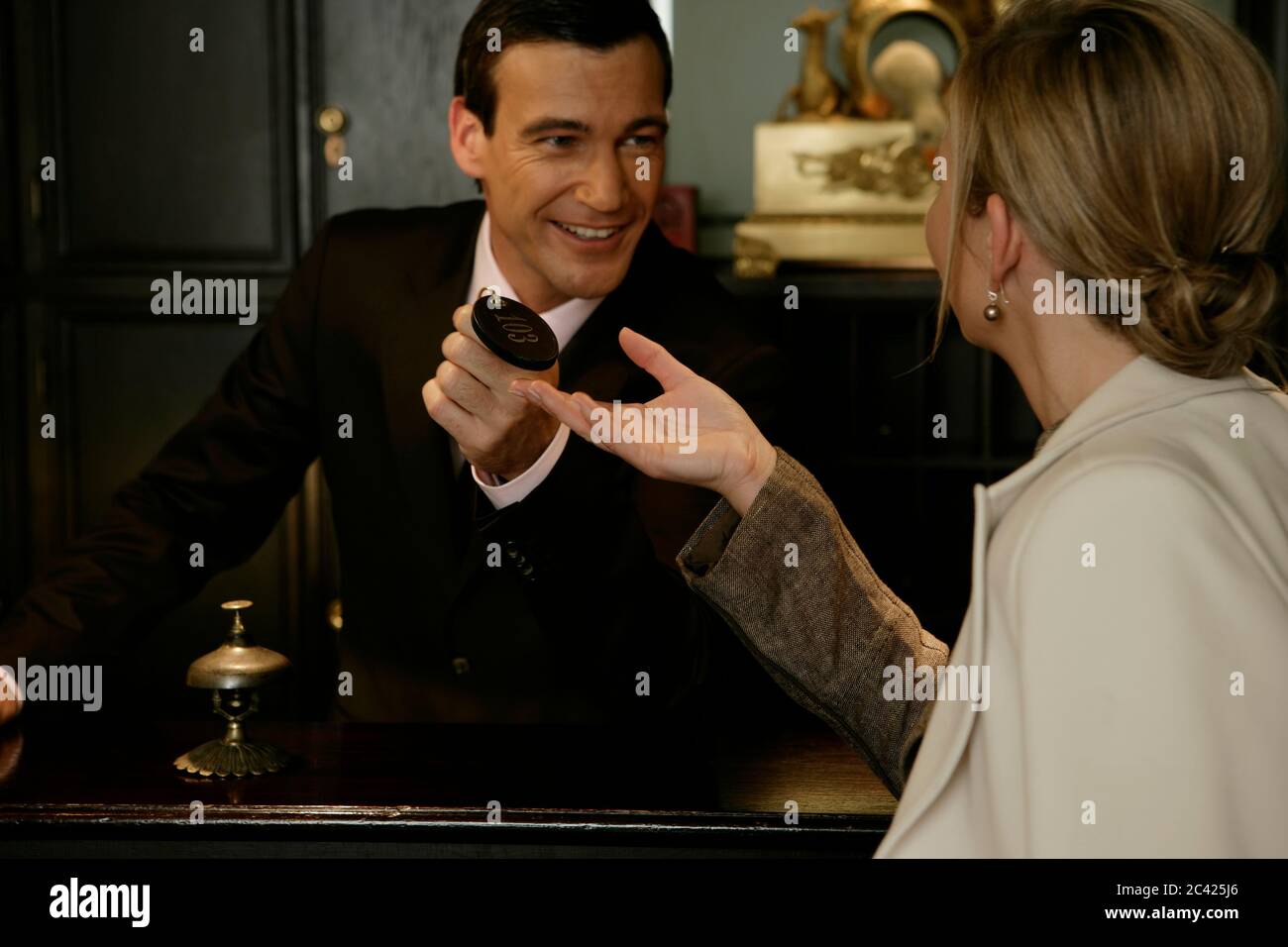 Concierge hands female hotel guest room key Stock Photo - Alamy