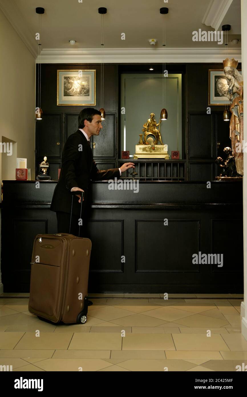 Middle-aged man rings the reception bell in a hotel Stock Photo - Alamy