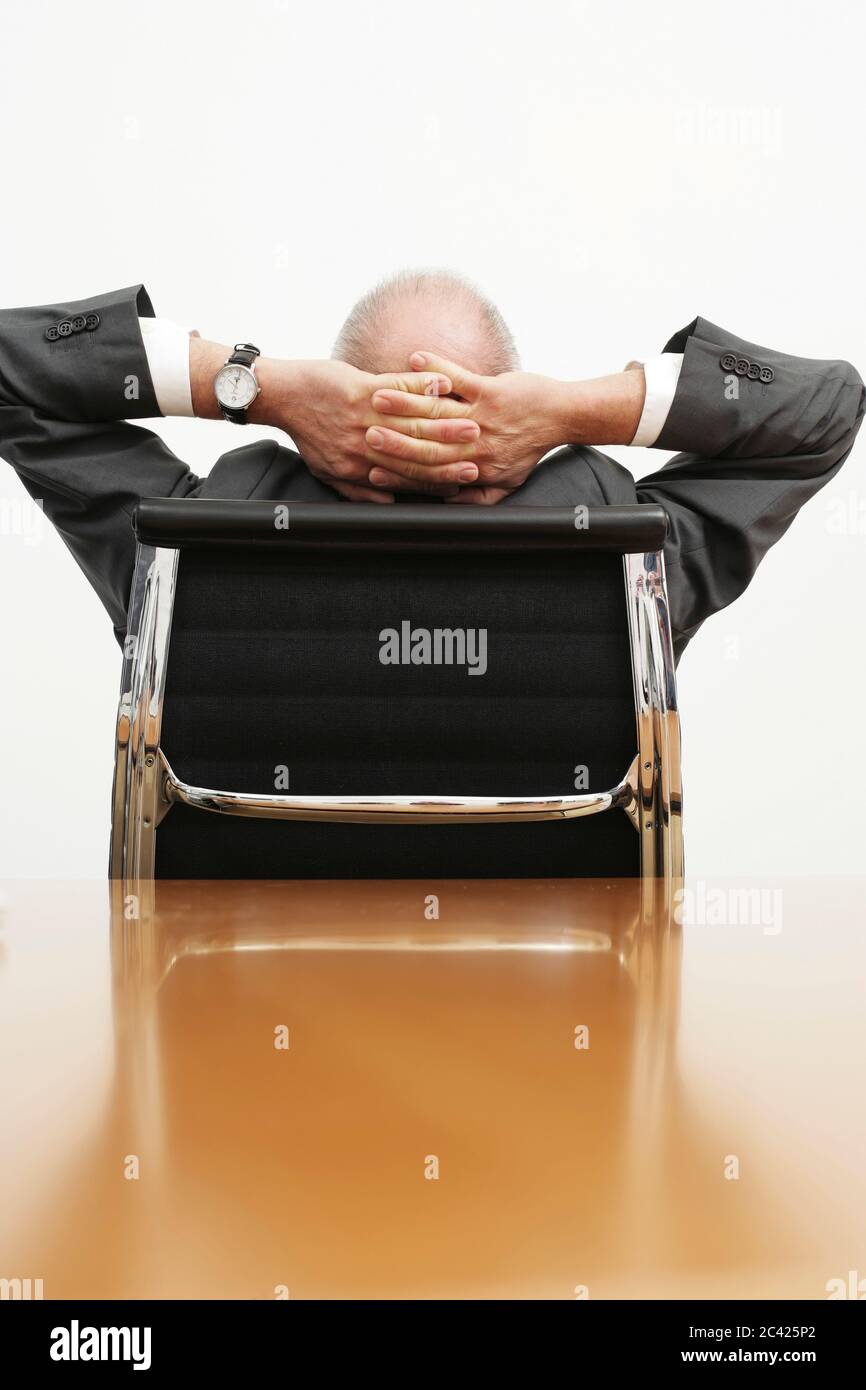 An older businessman leans back, back view - office - profession Stock ...