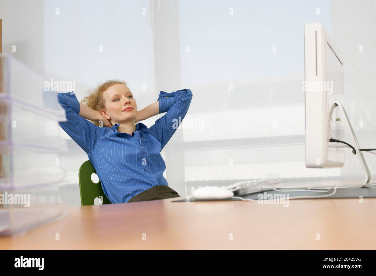 Young woman sitting in the office, leaning back Stock Photo - Alamy